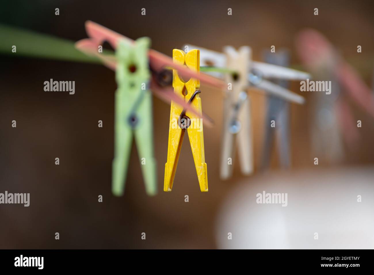 Selective view of colored clothespin hanging on a rope on the blurred ...