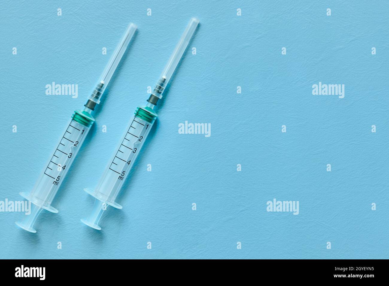 Two empty medical syringes close-up on blue background with space for ...