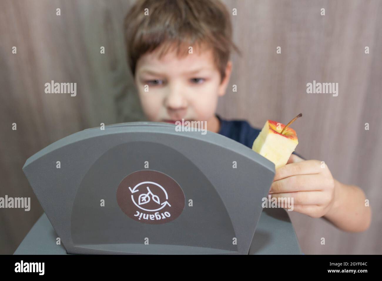 Child boy throwing apple core to waste bin for organic at home ...