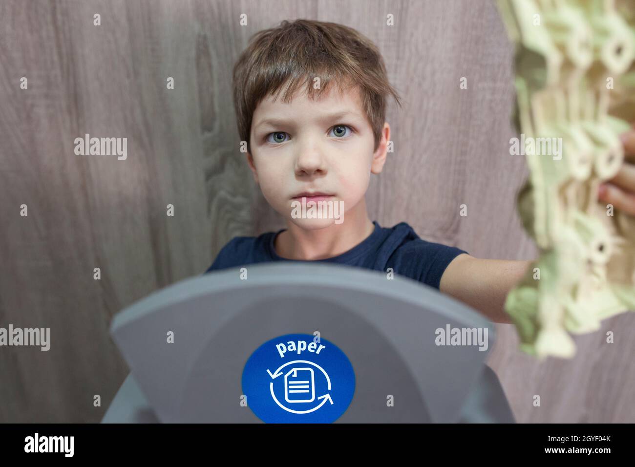 Child boy throwing egg carton to waste bin for paper at home. Education ...