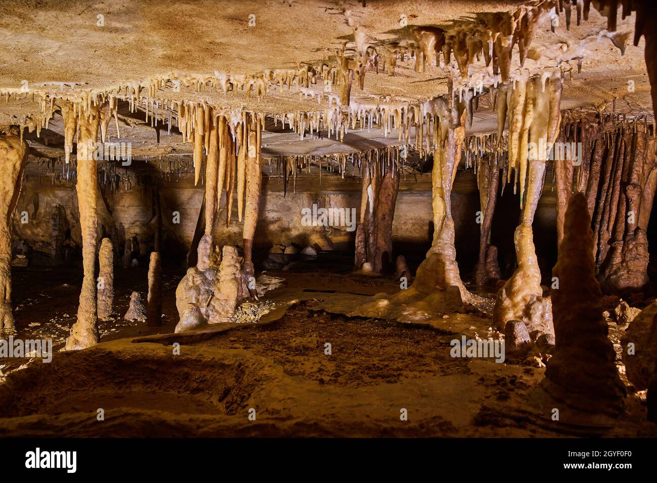 Formations of stalagmites and stalactites in cave with narrow walking ...