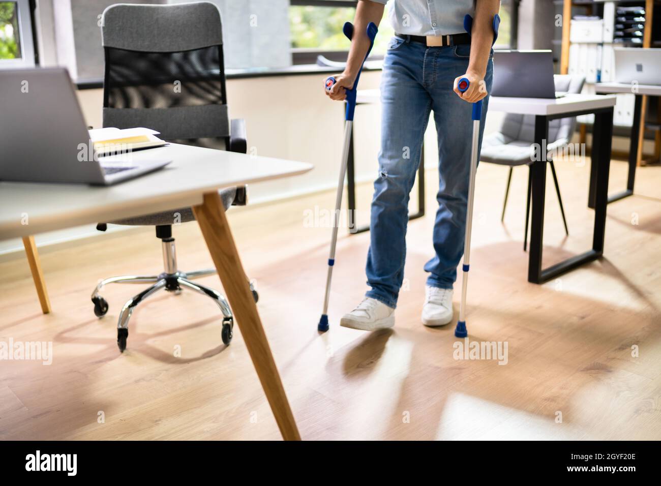 Worker With Crutches At Workplace Or Office. Handicap Rehabilitation ...