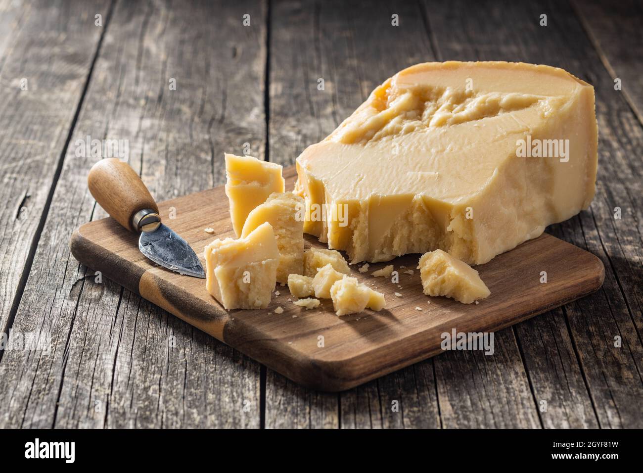 Pieces of italian parmesan cheese. Block of parmesan on wooden table ...