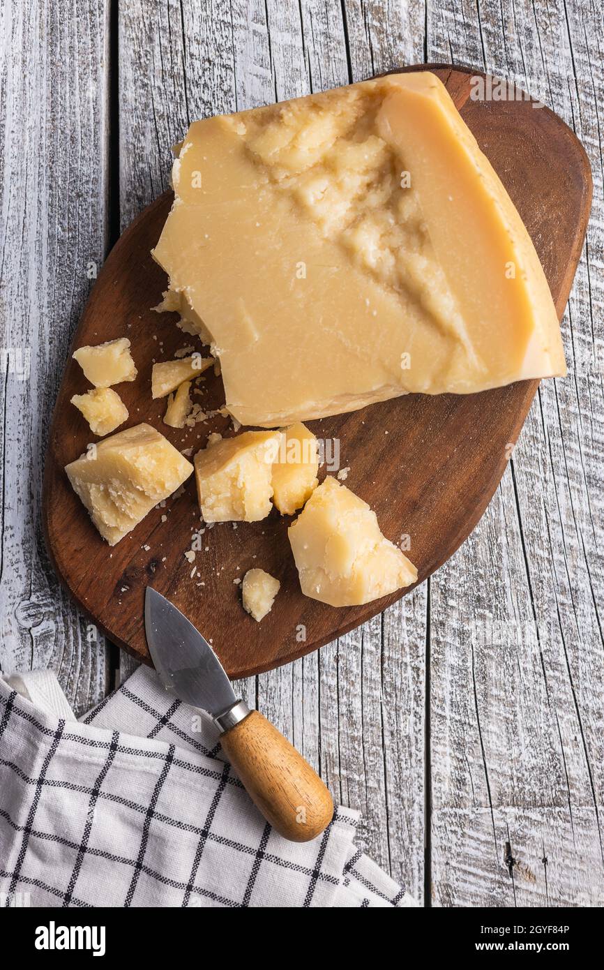 Pieces of italian parmesan cheese. Block of parmesan on wooden table ...