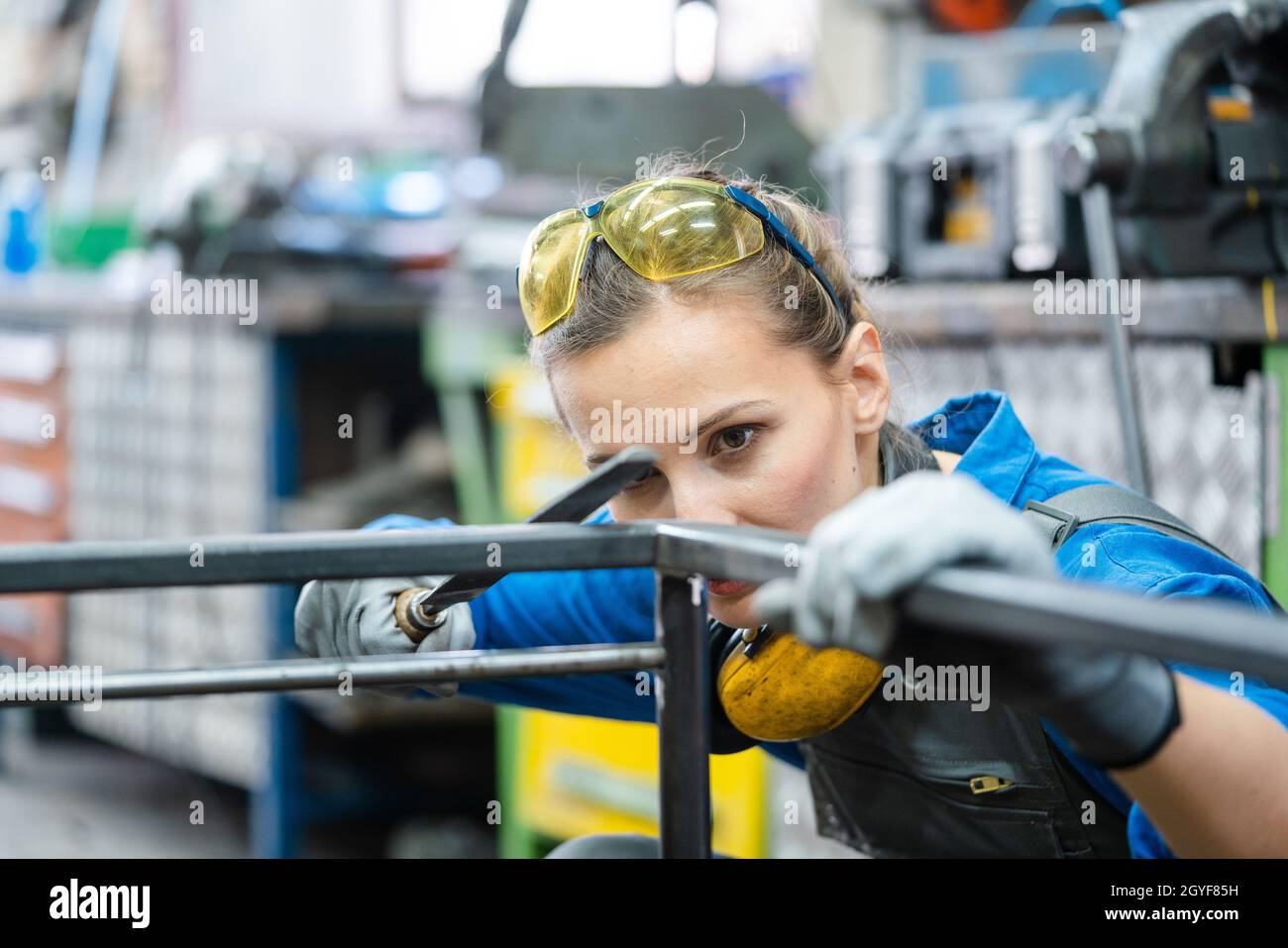 Woman metalworker checking the accuracy of her work holding steel file ...