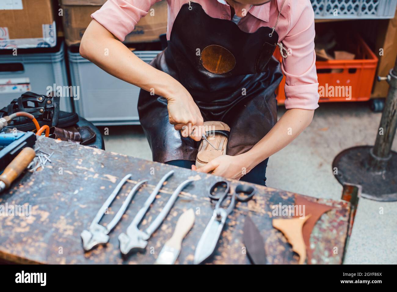 Shoemaker working on the frame of a shoe with lots of tools on the ...