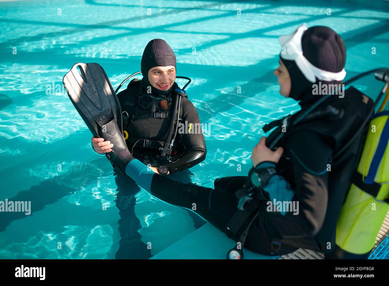 Male instructor helps woman to put on fins, diving school. Teaching ...