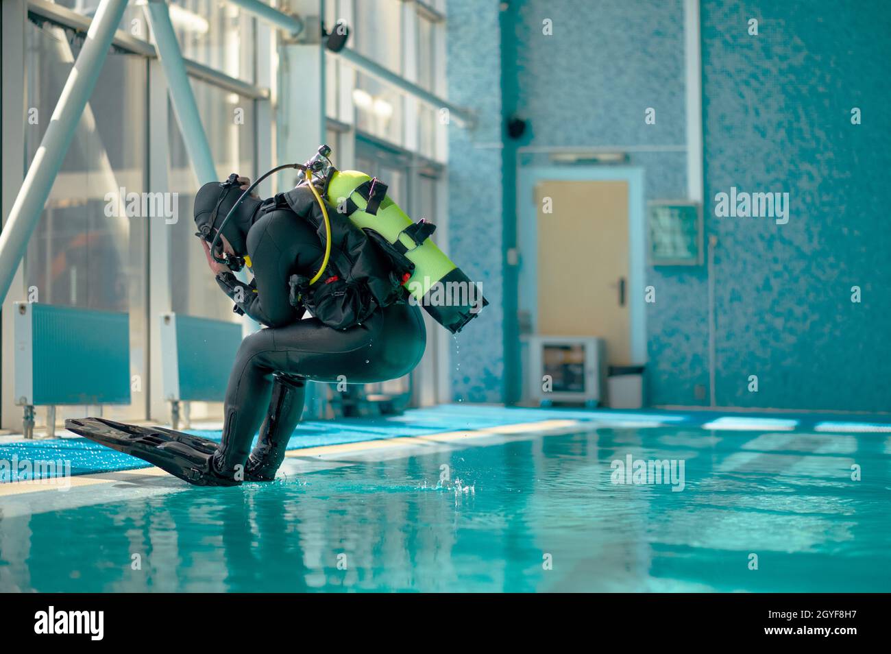 Male diver in scuba gear jumps into the pool, course in diving school ...