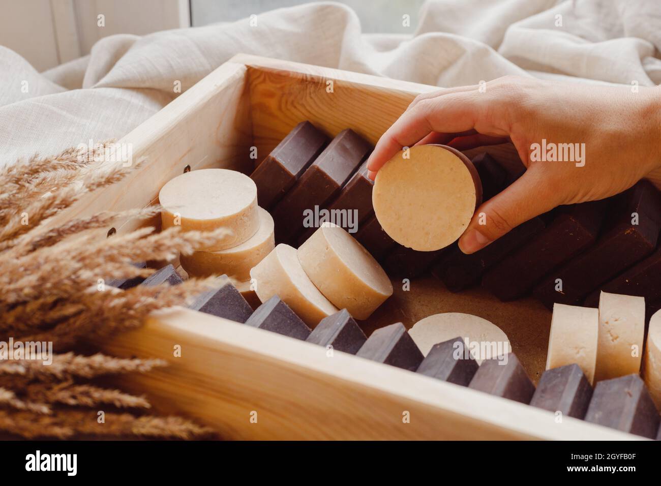Hand take homemade soap from wooden box full of natural solid shmpoo ...