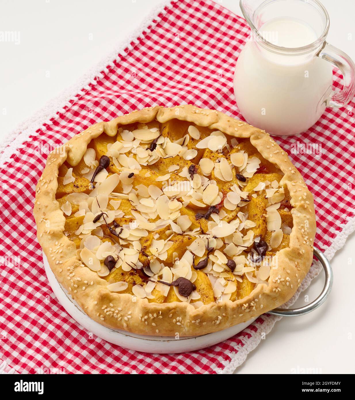 baked round pie with apple pieces, sprinkled with almond flakes on a ...