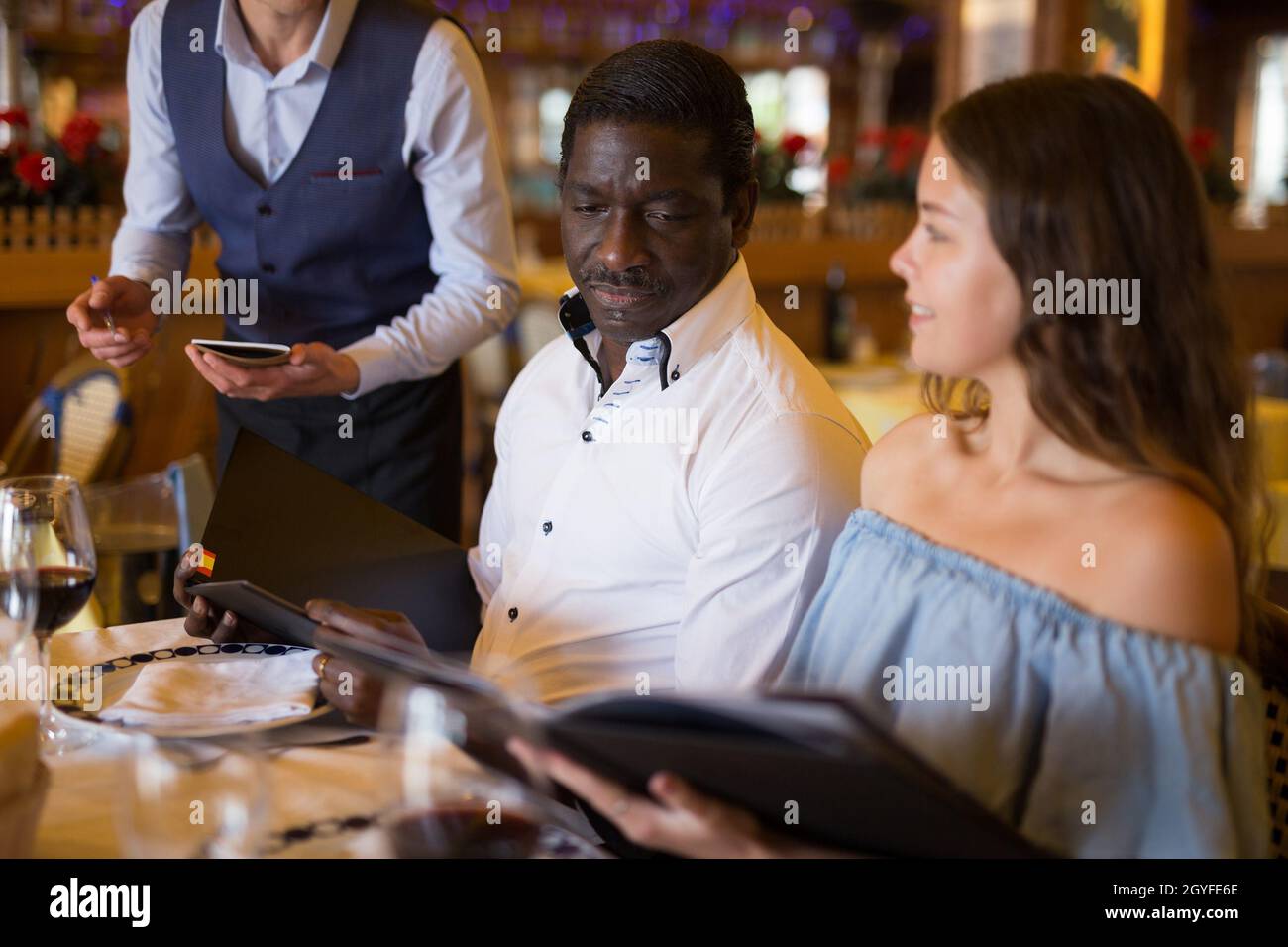 Male waiter writing down order from visitors in restaurant Stock Photo ...