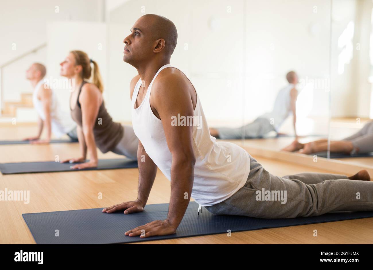 Man making yoga exercises at group class Stock Photo - Alamy