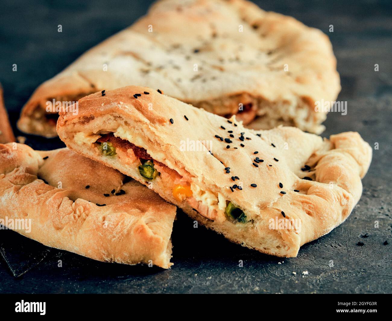 Perfect homemade closed pizza calzone on baking paper sheets over black ...
