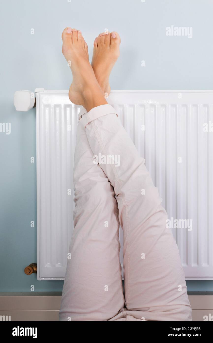 Woman Warming Up Her Feet On White Radiator At Home Stock Photo - Alamy