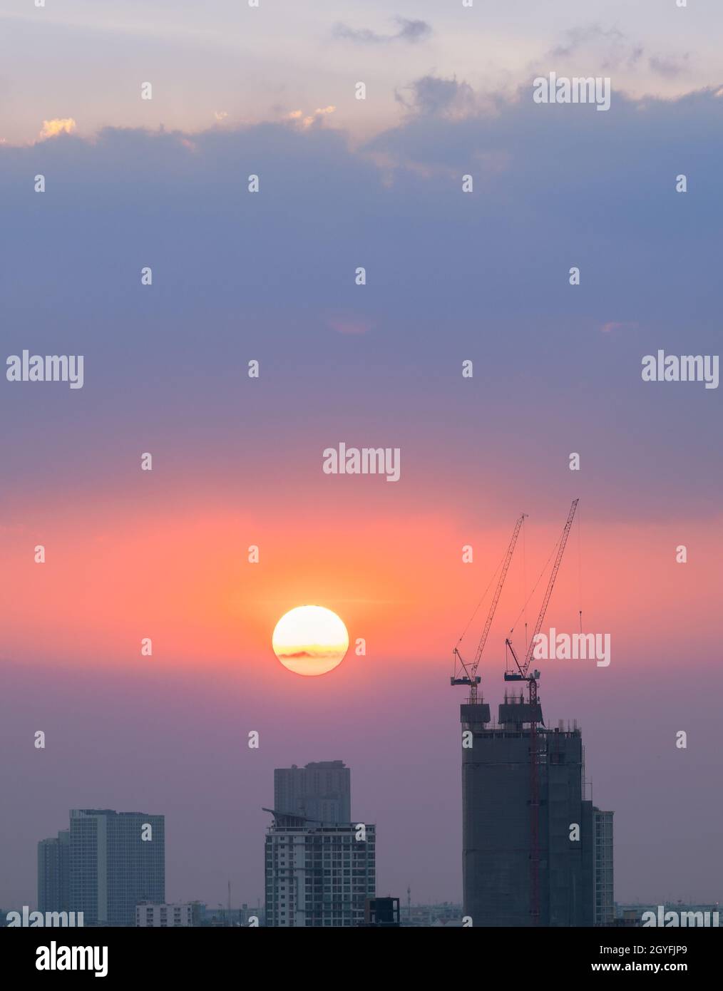 Sunset skyline over high rise buildings and construction site with ...