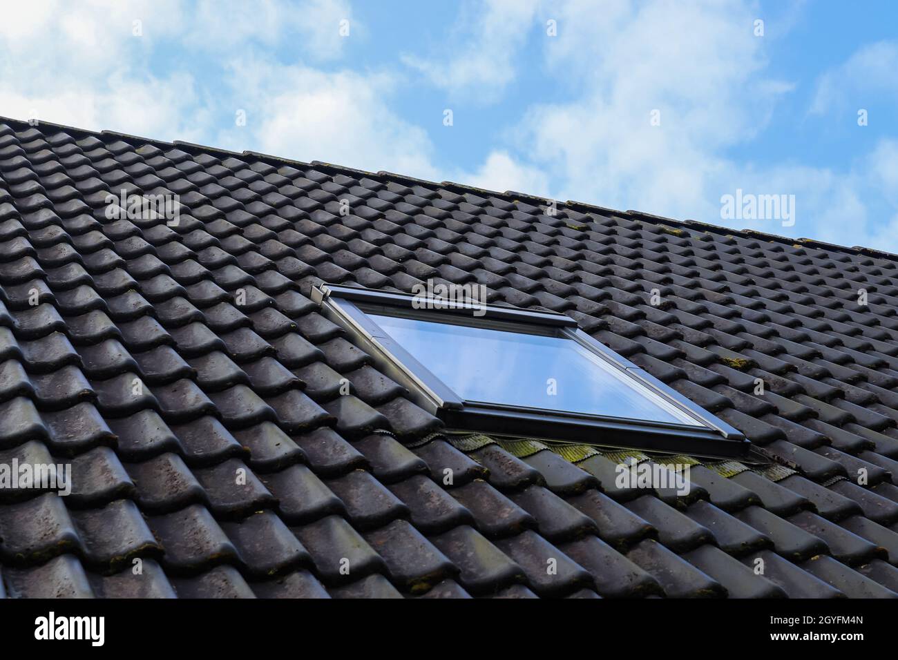 Roof window in velux style with black roof tiles Stock Photo - Alamy