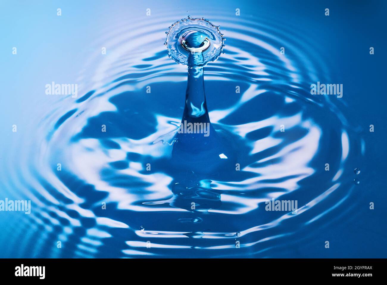 Two water drops crashing and creating ripples on clean blue water Stock ...