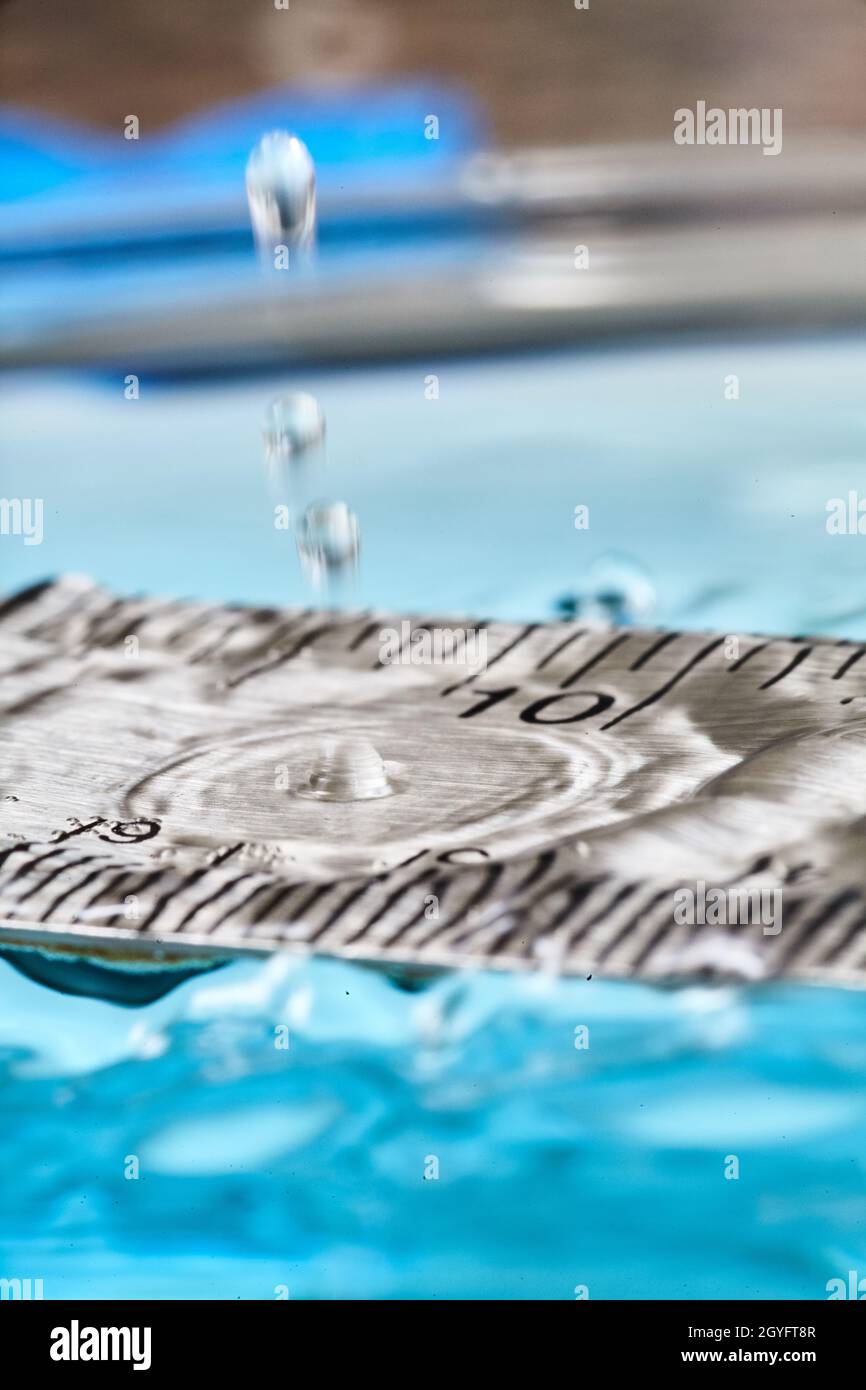 Three midair water droplets and a fourth pressed against a ruler all ...