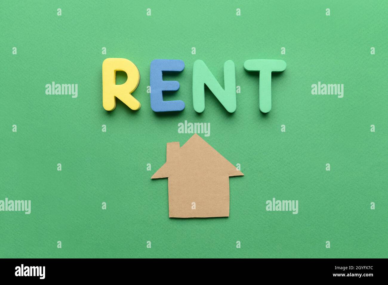 Wooden house and word RENT on green background Stock Photo - Alamy