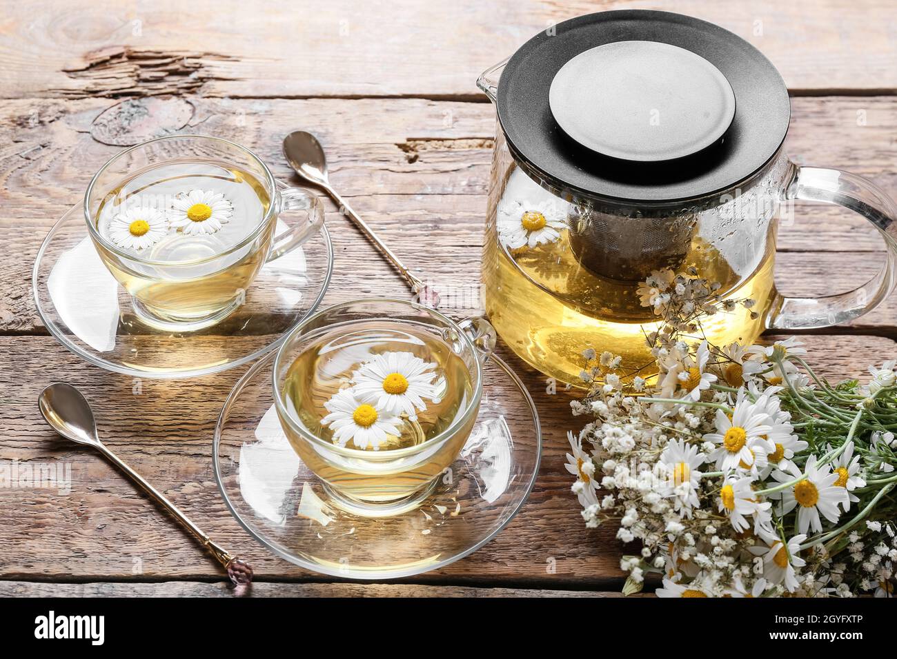 Teapot and cups of fresh chamomile tea with flowers on wooden background Stock Photo - Alamy