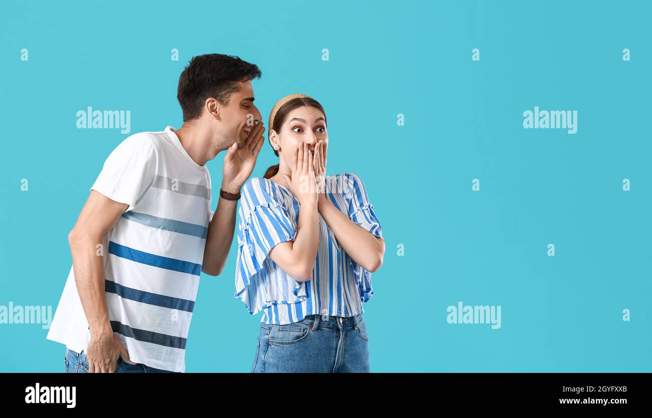 Young man sharing gossip with his girlfriend on blue background Stock ...