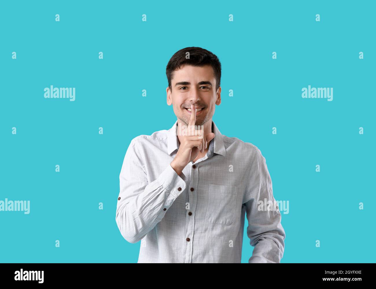 Young gossip man showing silence gesture on blue background Stock Photo ...