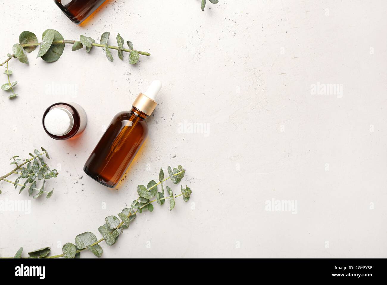 Bottles of essential oil and fresh eucalyptus branches on light ...