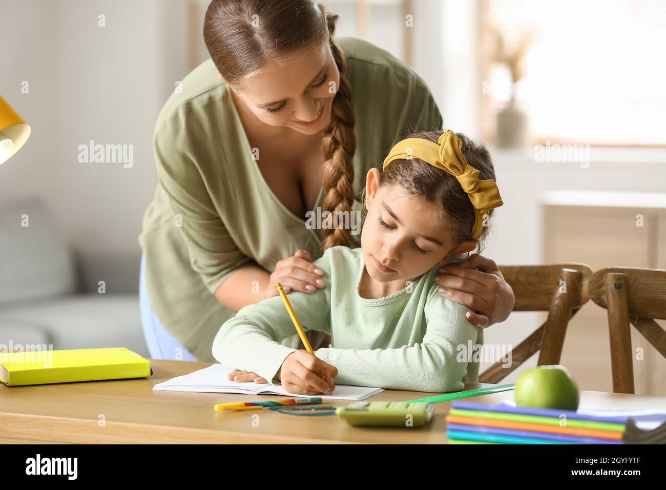 Little girl with her mother doing lessons at home Stock Photo - Alamy