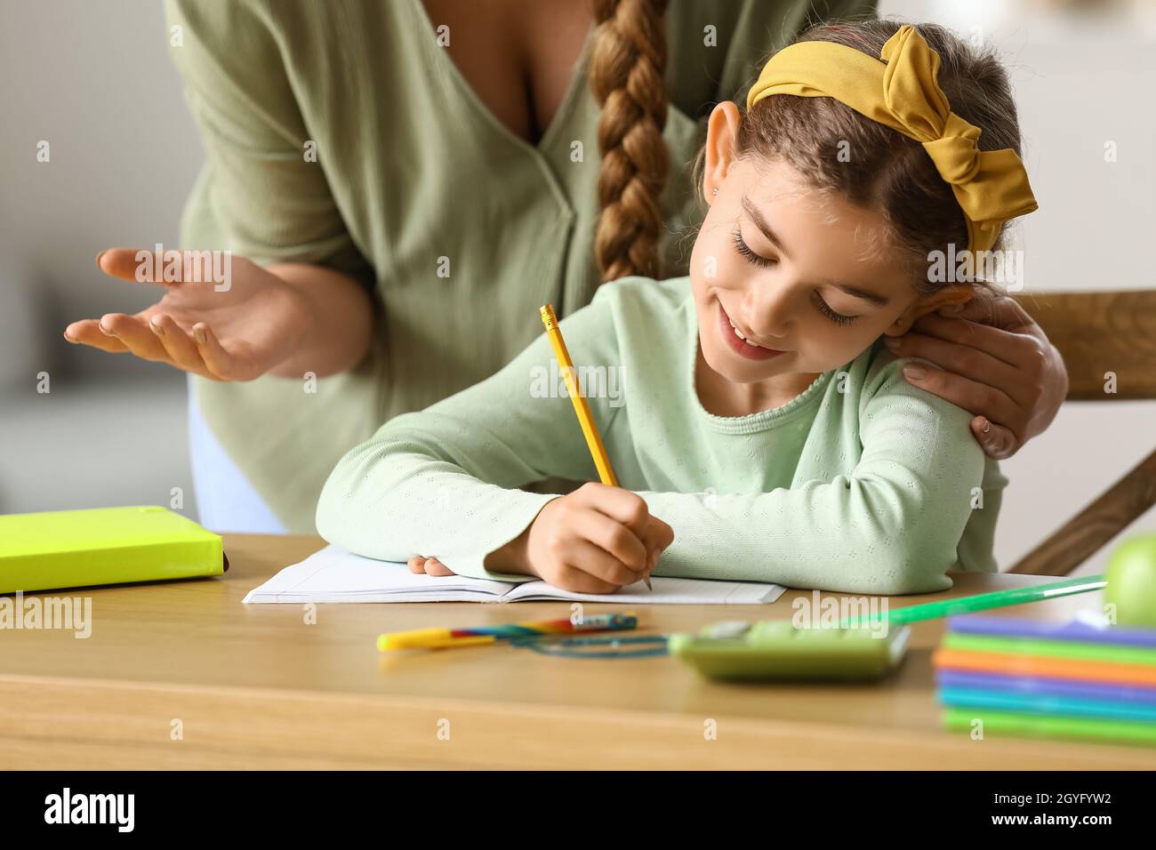 Little girl with her mother doing lessons at home Stock Photo - Alamy