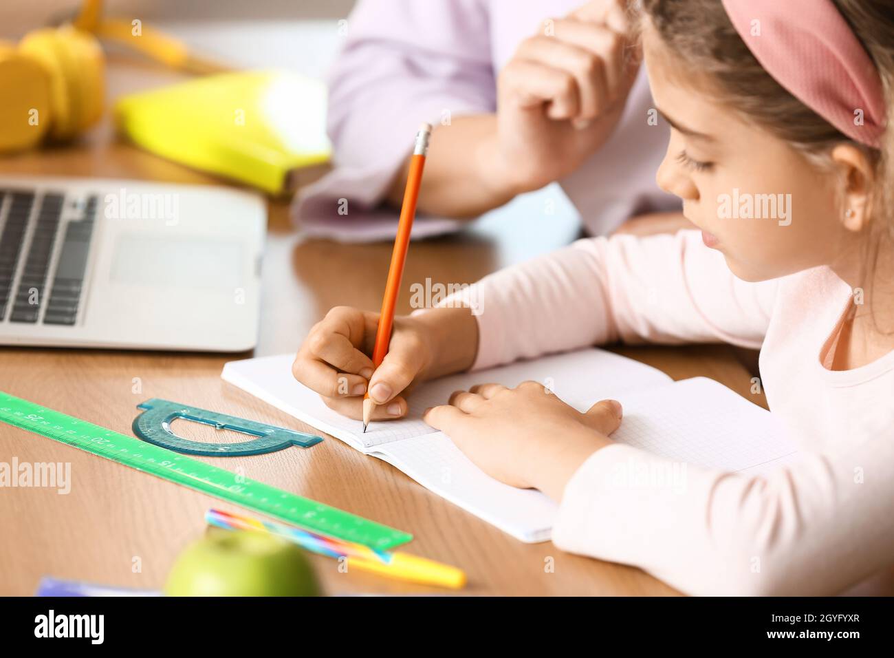 Little girl with her mother doing lessons at home Stock Photo - Alamy