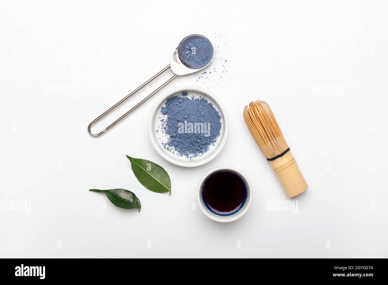 Composition with cup of blue matcha tea, powder and chasen on white ...