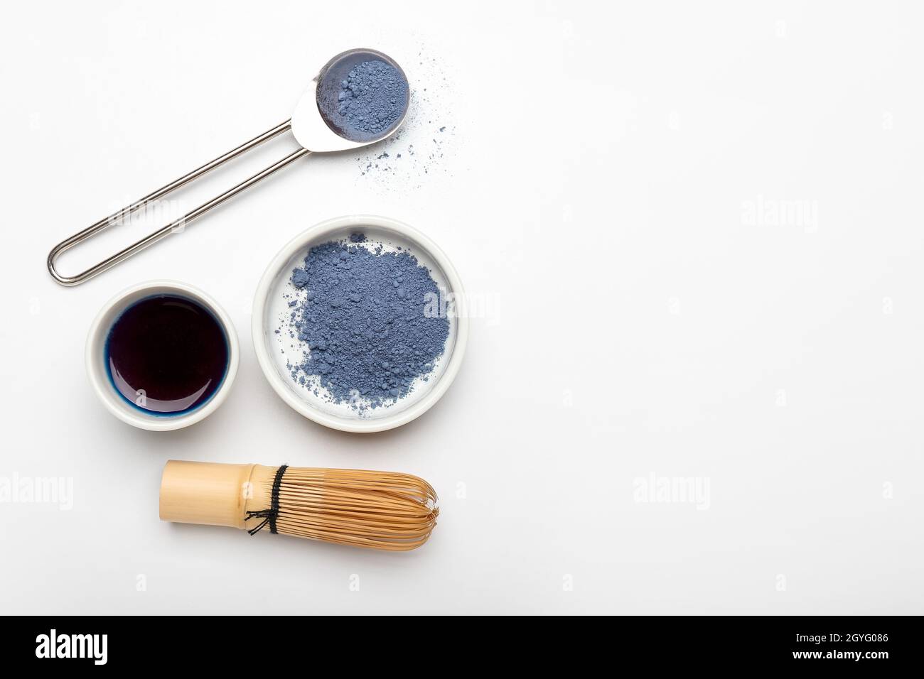 Composition with cup of blue matcha tea, powder and chasen on white ...