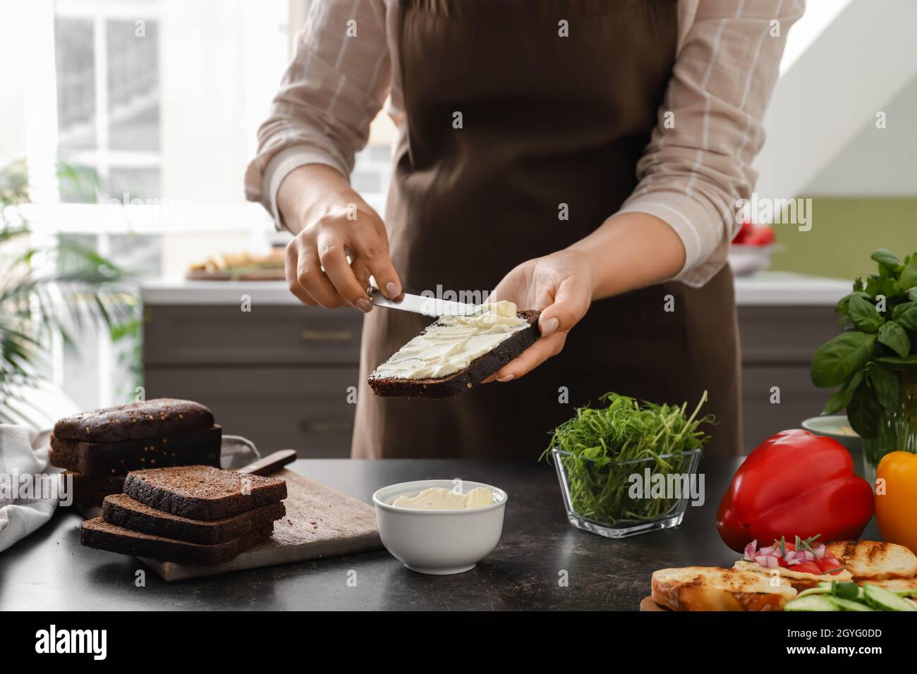 Woman spreading toast with dip at table in kitchen Stock Photo - Alamy