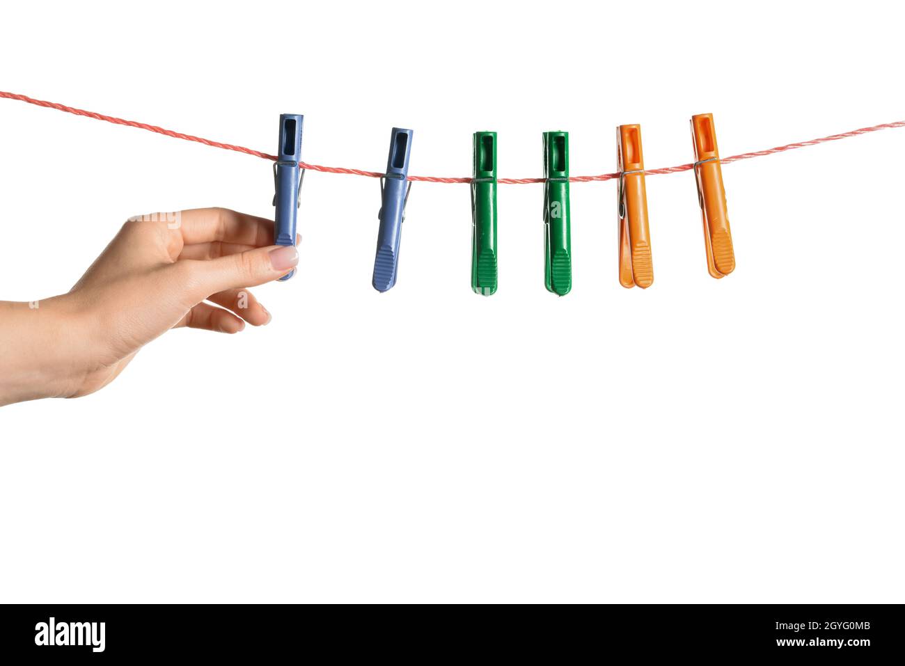 Woman hanging clothespins on laundry line against white background ...