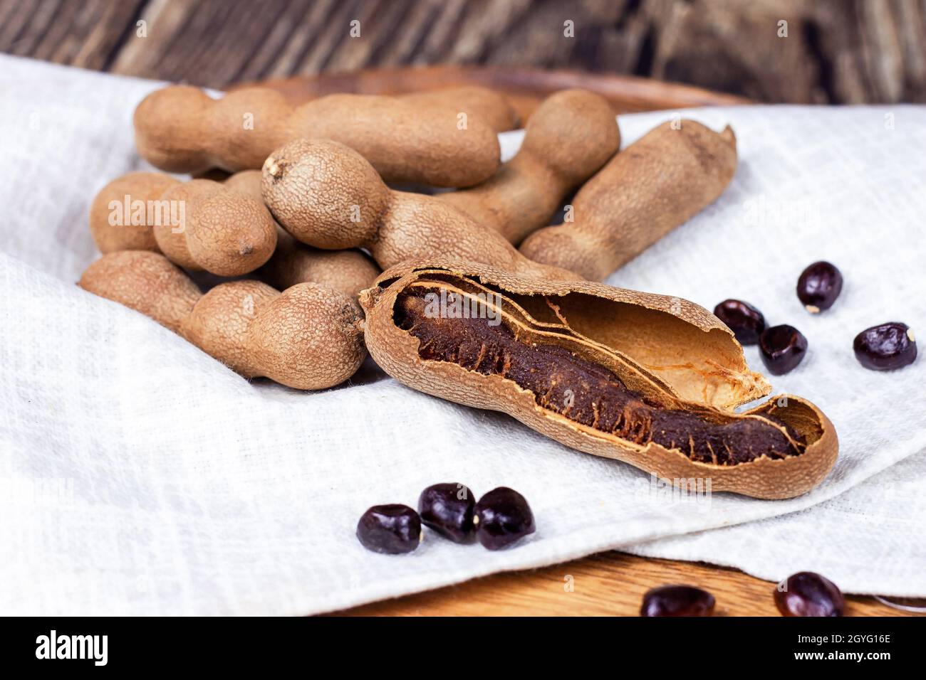 Fresh brown tamarind fruit pods ripe with seeds on light textile ...