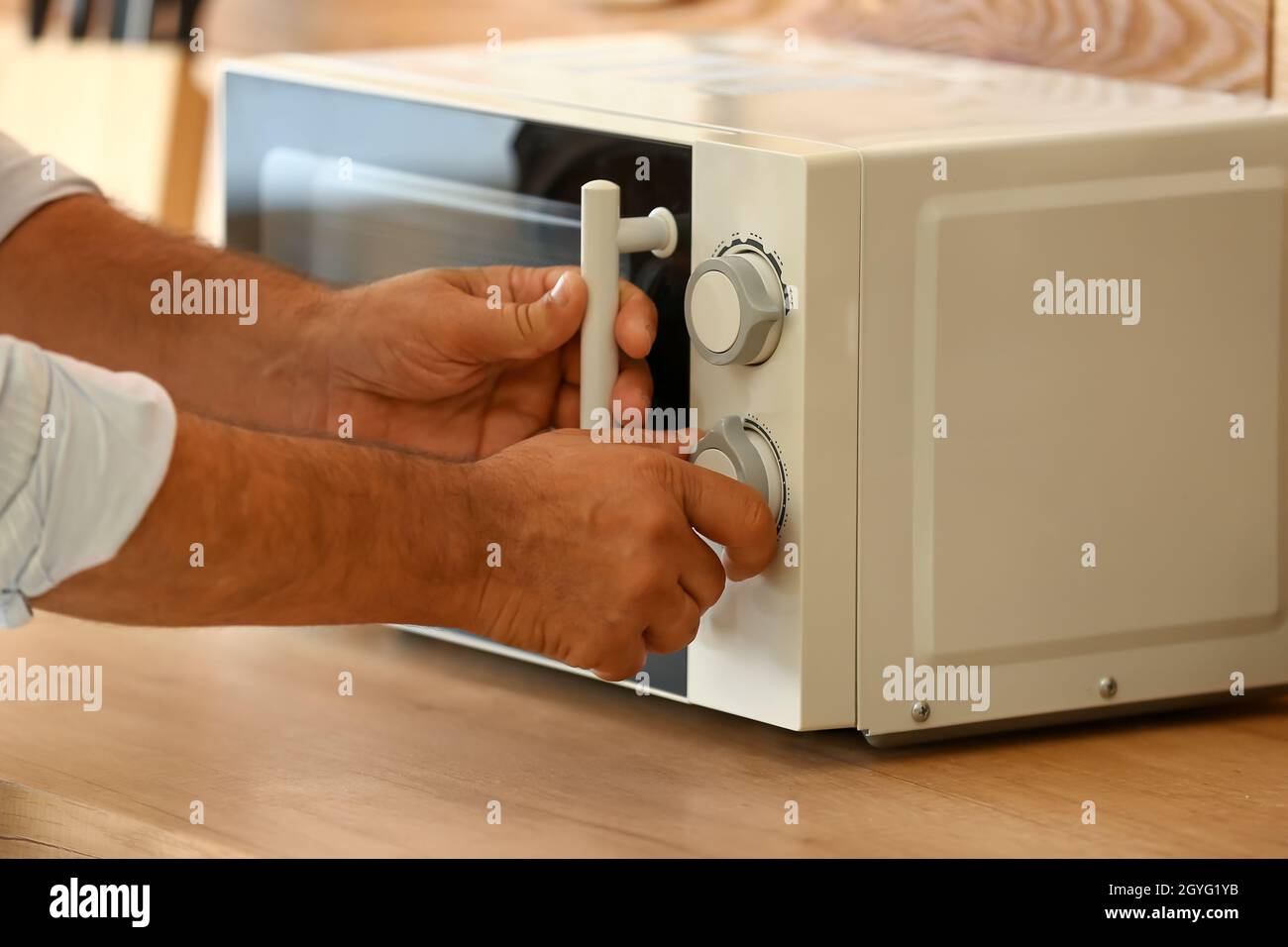 Mature man heating food in microwave oven, closeup Stock Photo - Alamy