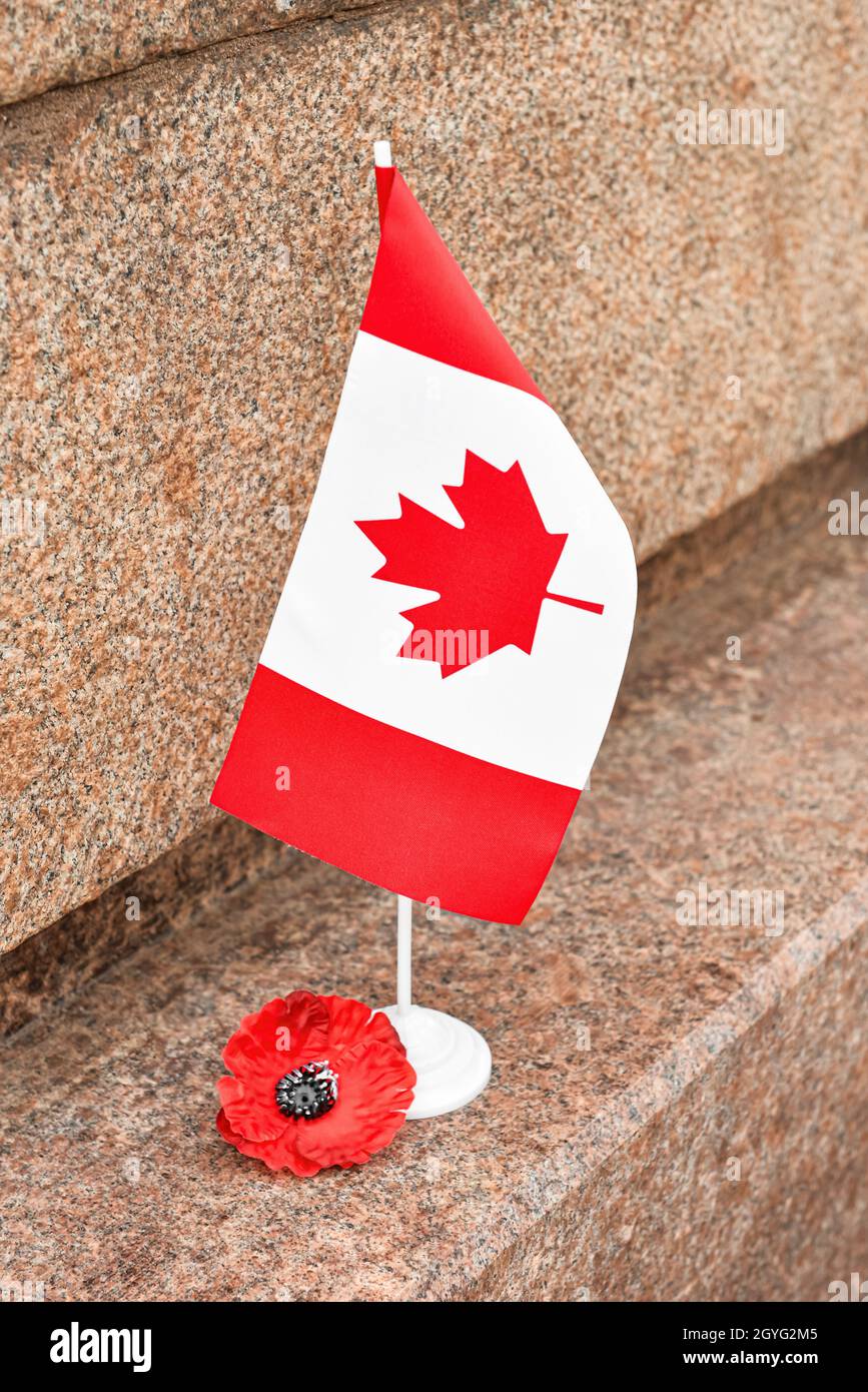 Poppy flower and flag of Canada on stone monument. Remembrance Day ...