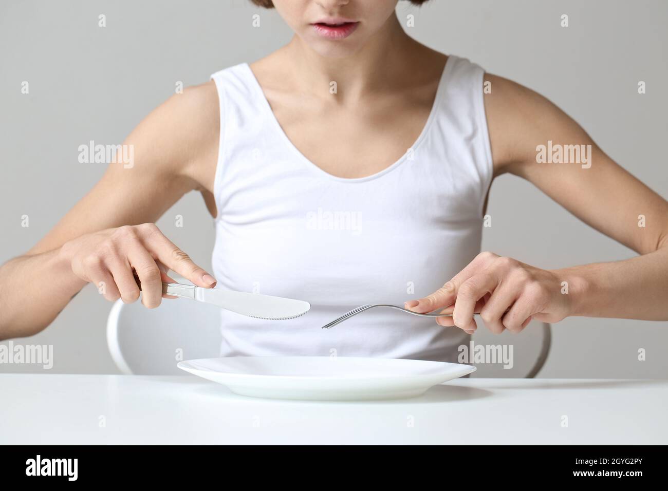 Young woman with empty plate at table. Anorexia concept Stock Photo - Alamy