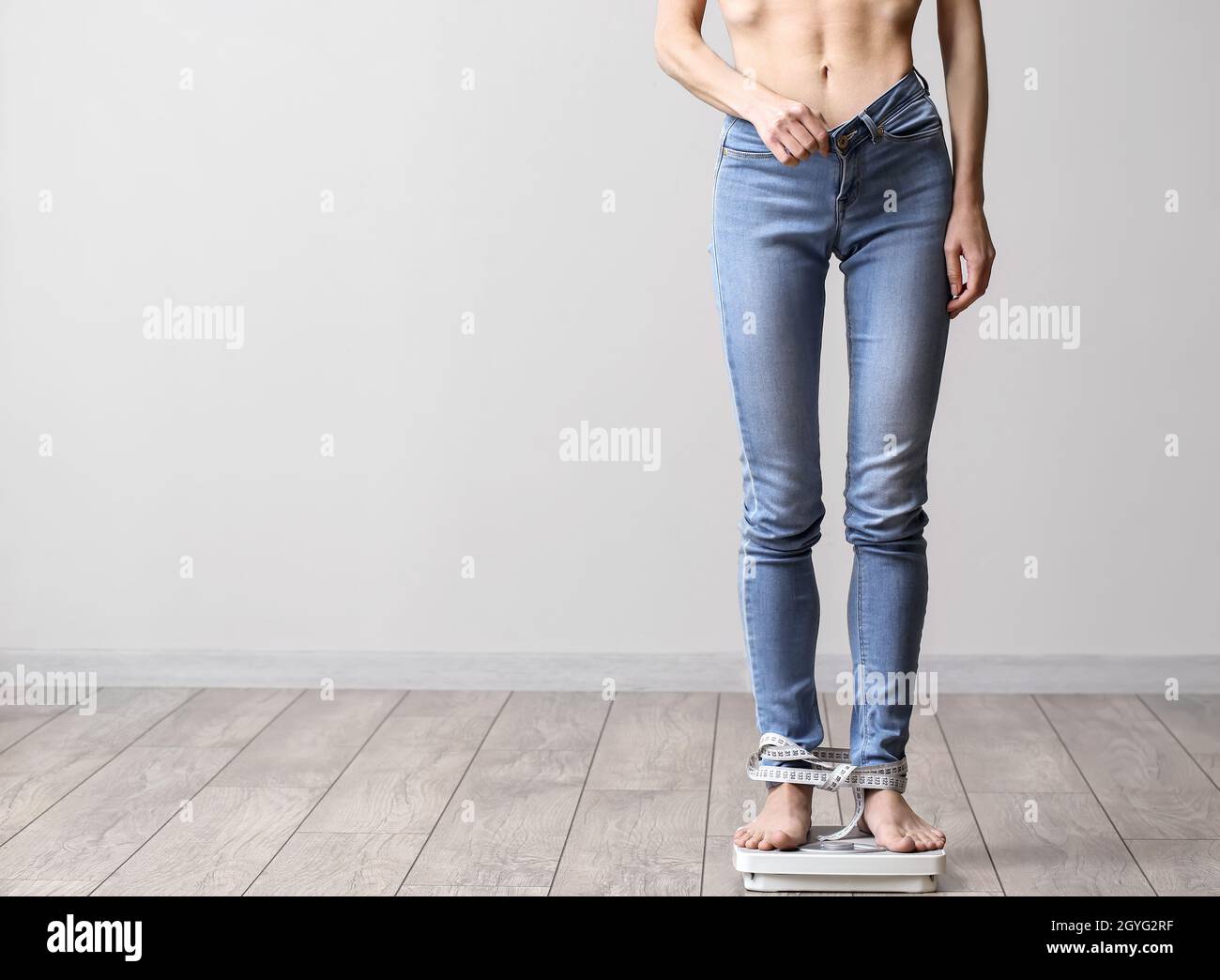 Young woman with anorexia measuring her weight on grey background Stock ...