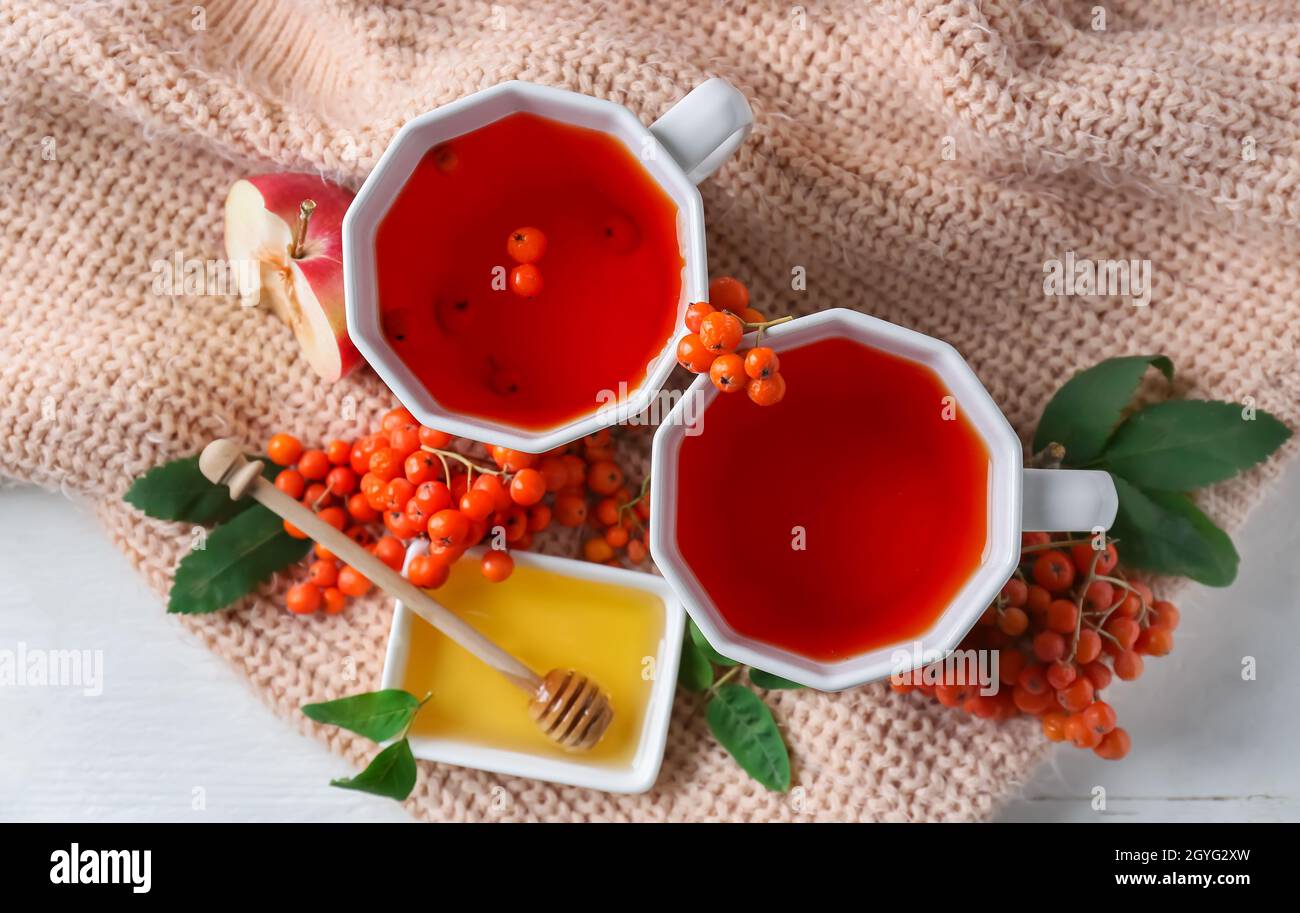 Composition with cups of tasty rowan tea, honey and berries on light ...