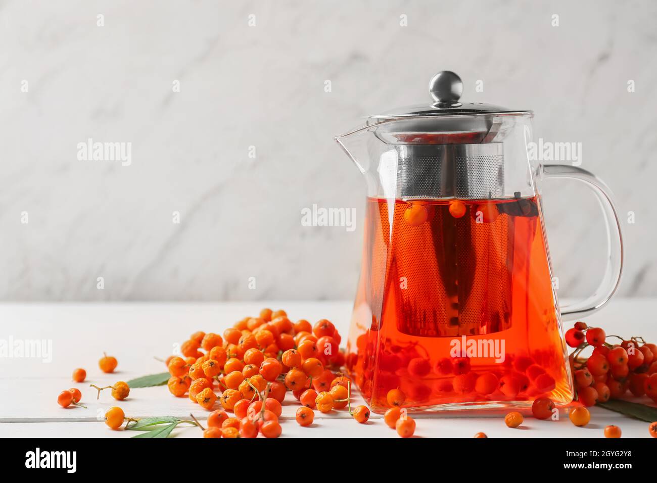 Glass teapot with hot rowan tea and berries on light background Stock ...