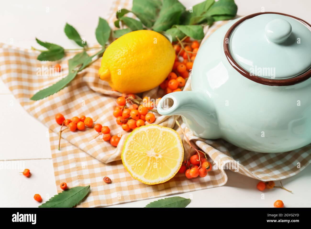 Composition with teapot of tasty rowan tea, berries and lemon on light ...
