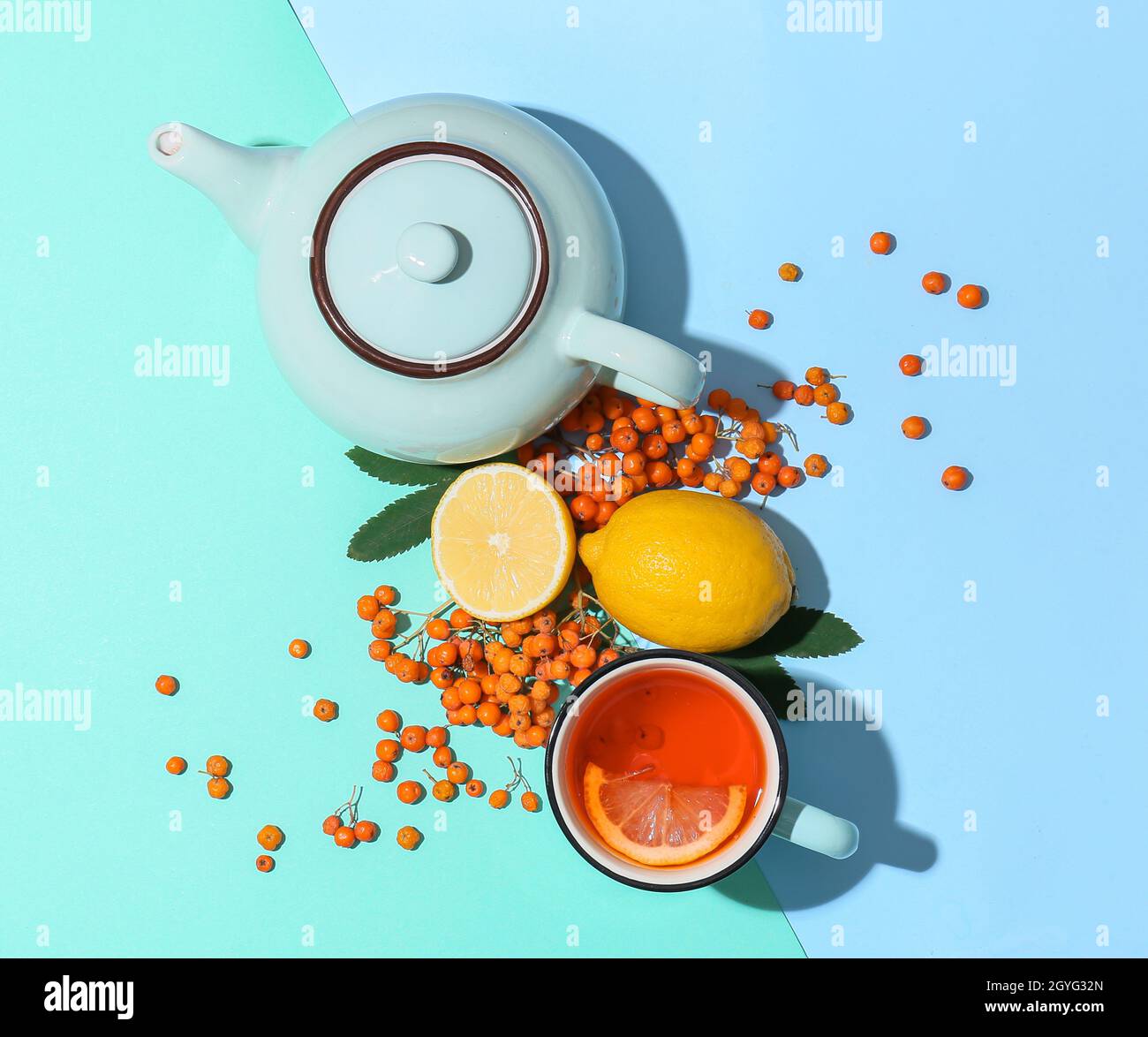 Composition with cup of tasty rowan tea, berries and lemon on blue ...