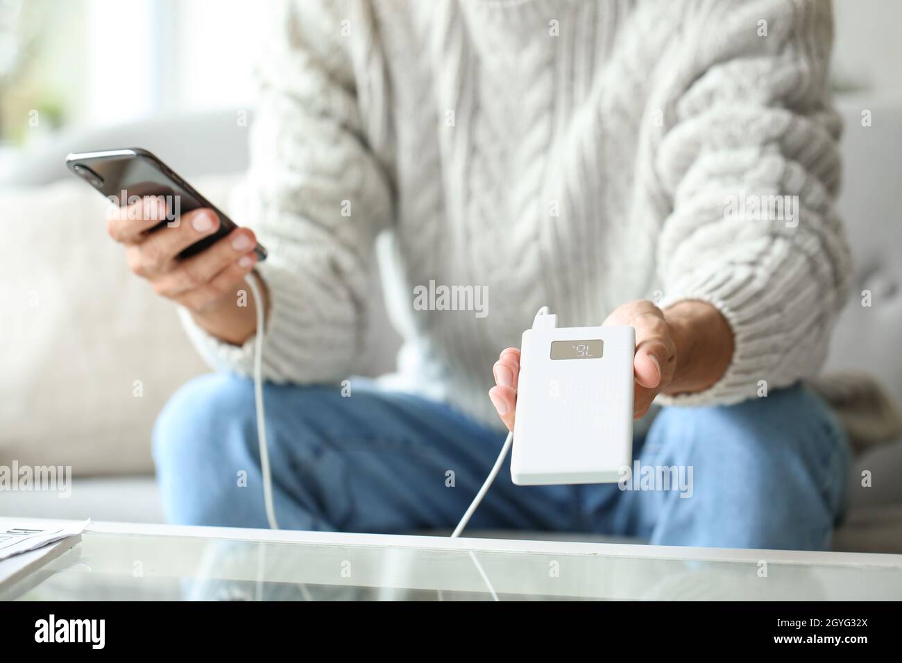 Young man with phone and power bank at home Stock Photo - Alamy
