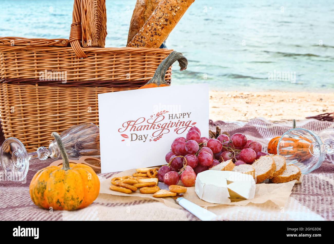 Wicker basket, delicious food and card with text HAPPY THANKSGIVING DAY ...