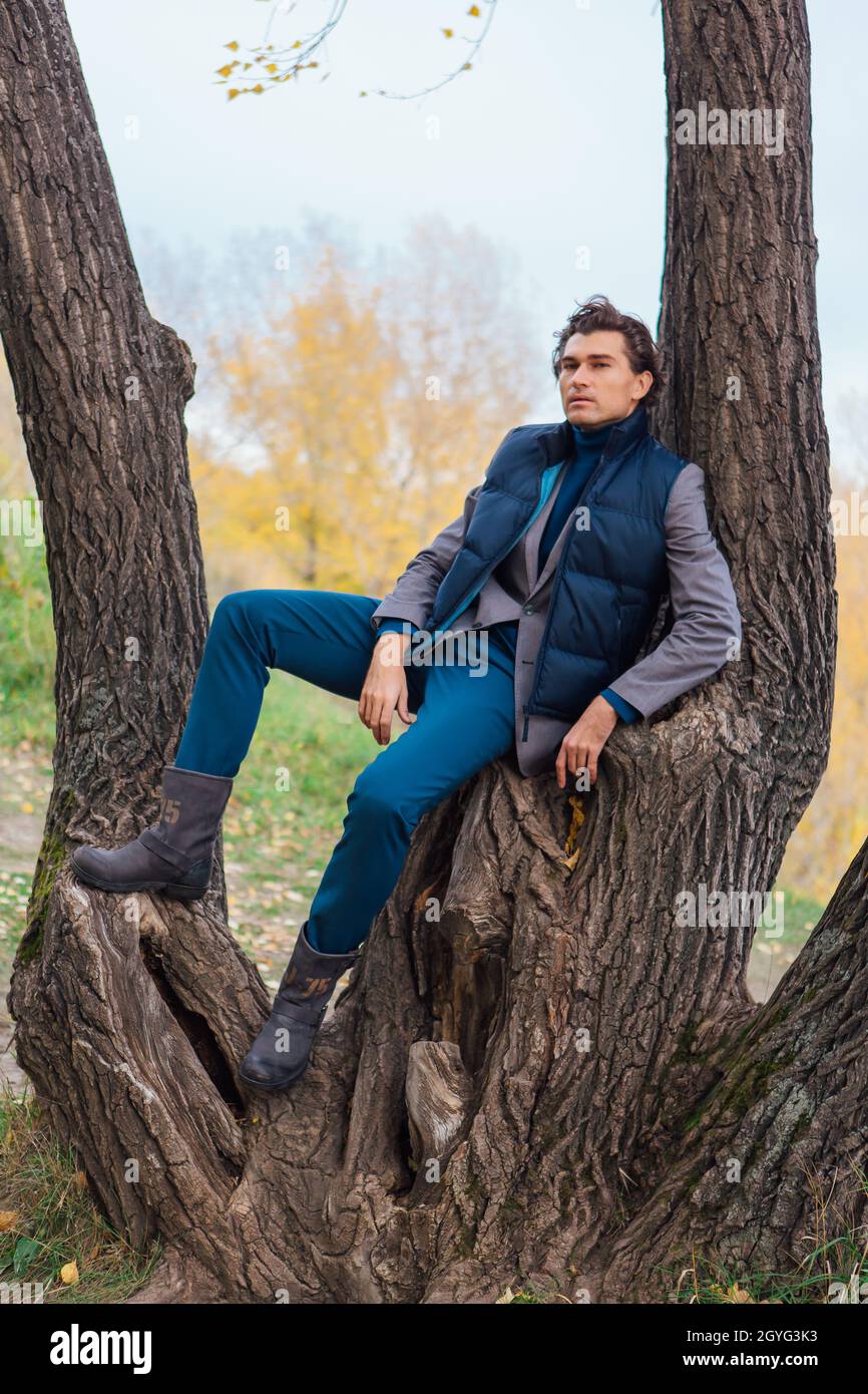 Tall handsome man climbing on the tree in yellow autumn forest Stock ...