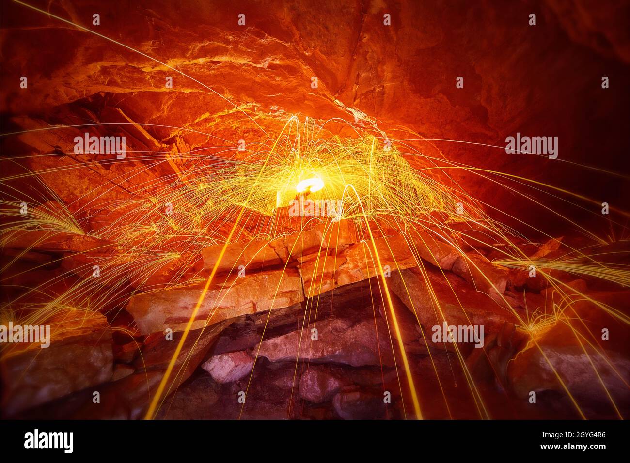 Steel wool sparks in a cave with yellow sparks flowing over stones ...
