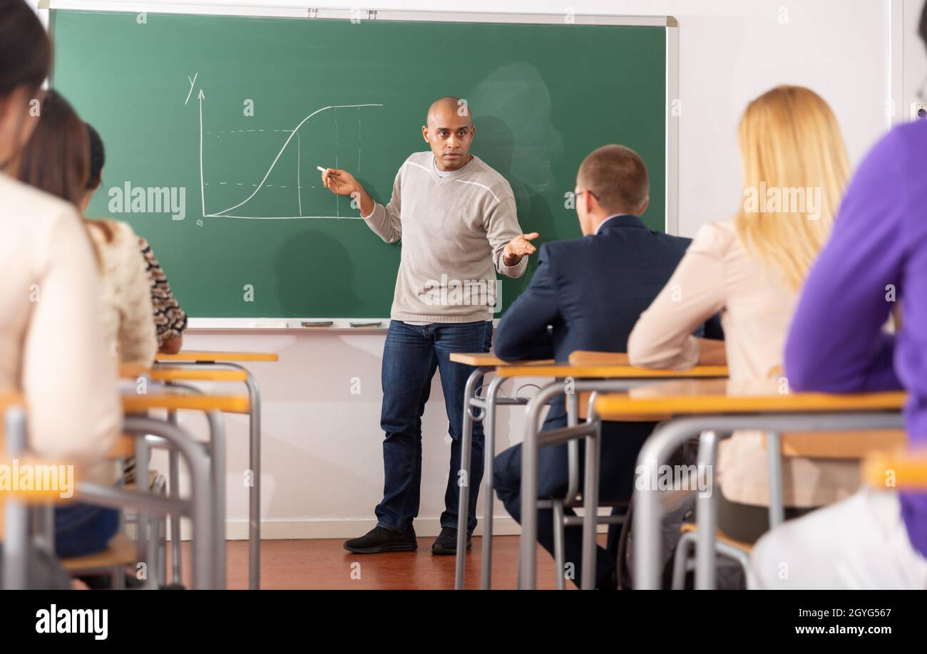 Teacher explaining new theme to adult students Stock Photo - Alamy