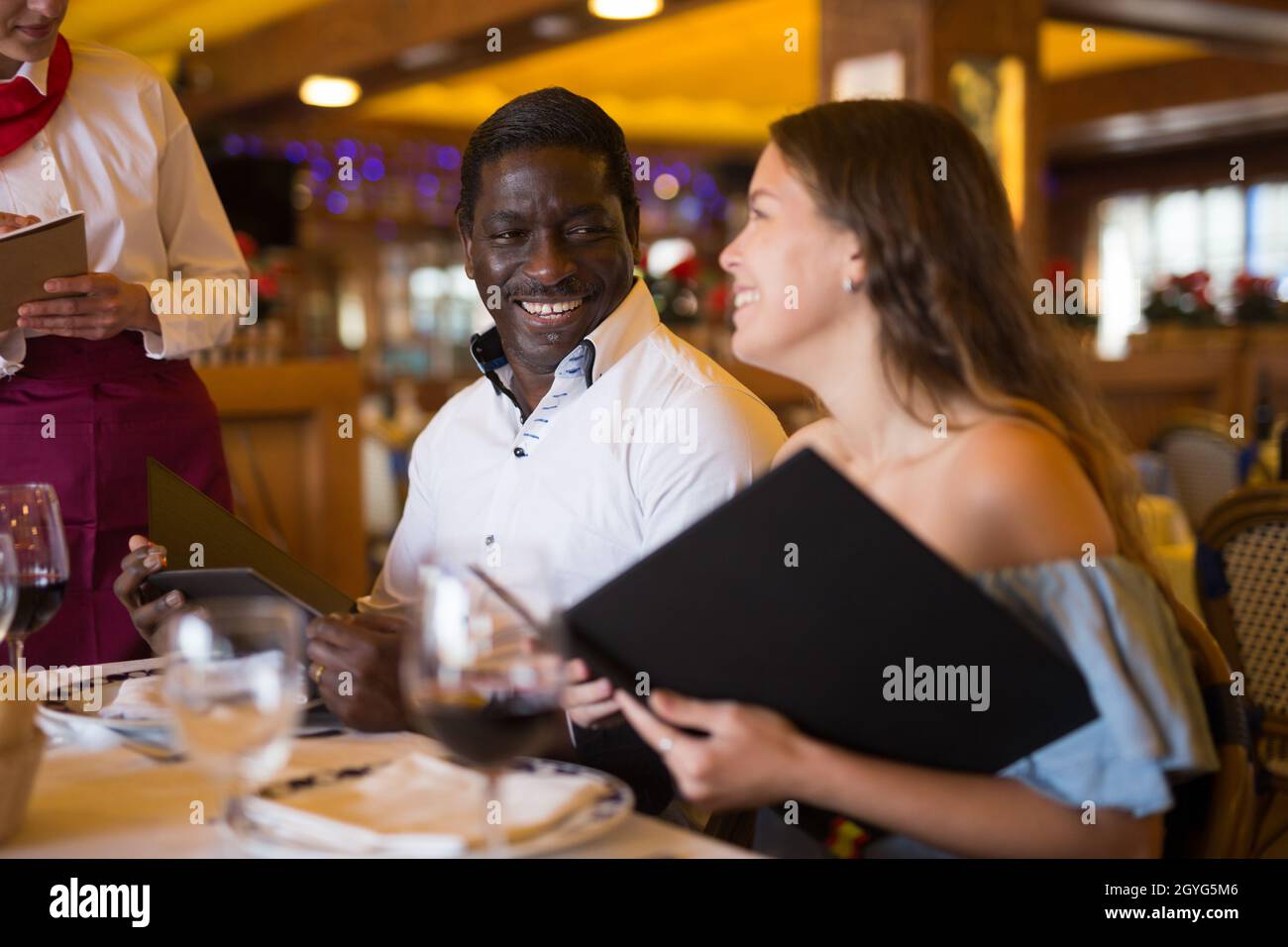Positive young couple making order at restaurant Stock Photo - Alamy