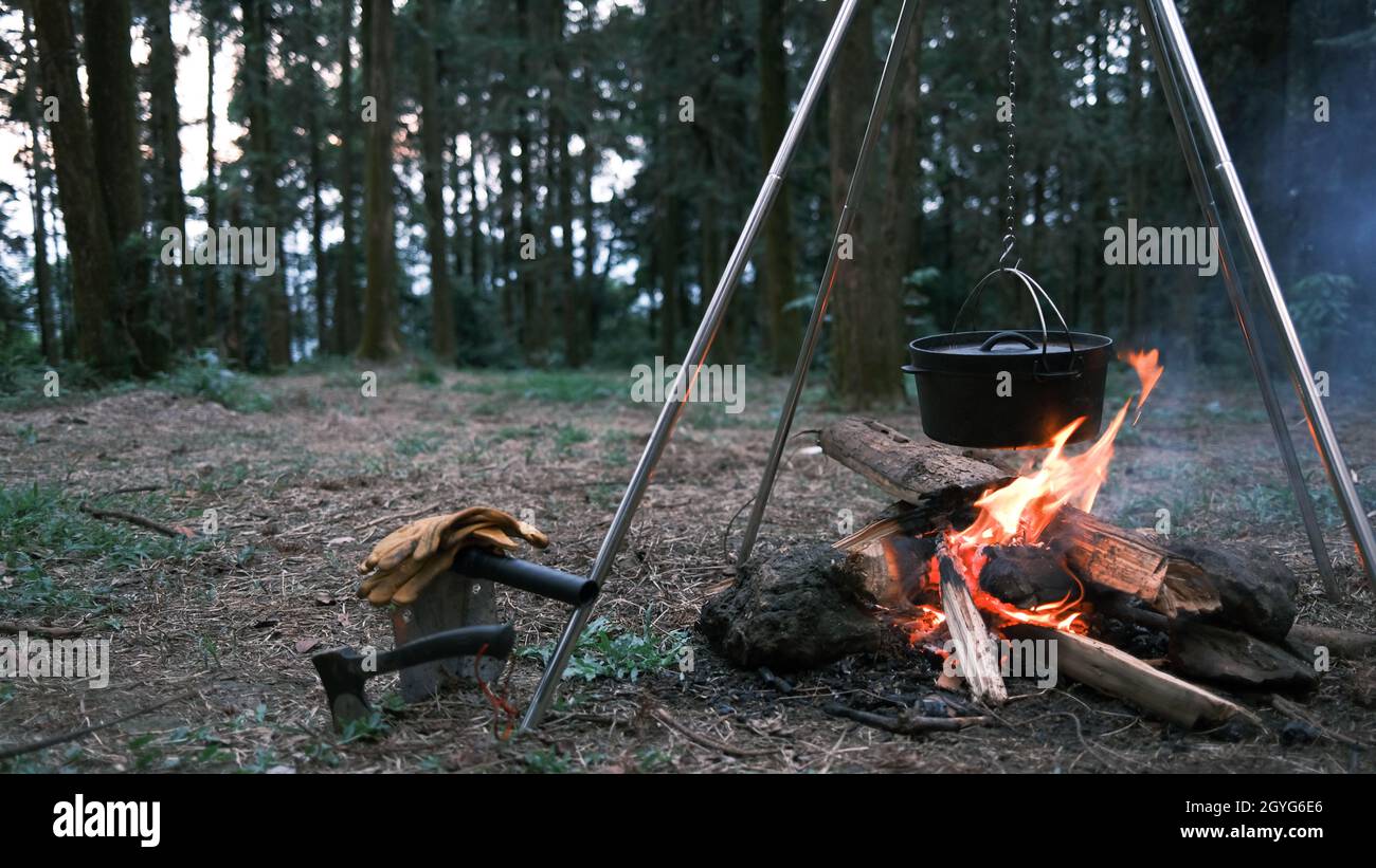 Cooking pot hanging over a campfire on a tripod at a tourist camp, a ...